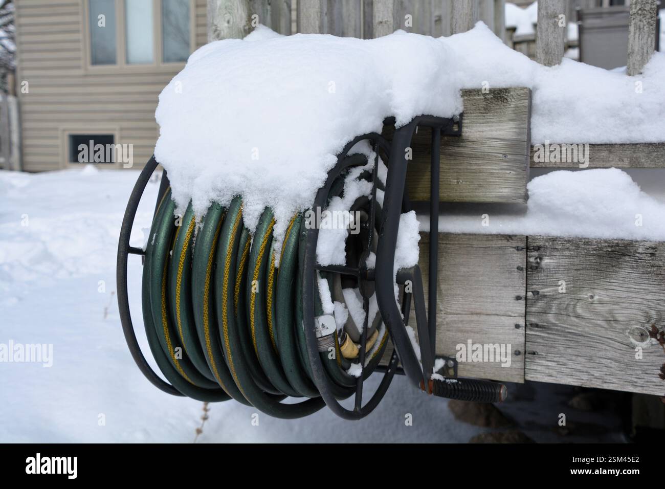 Snow builds up on an outside garden hose and reel during a Canadian ...