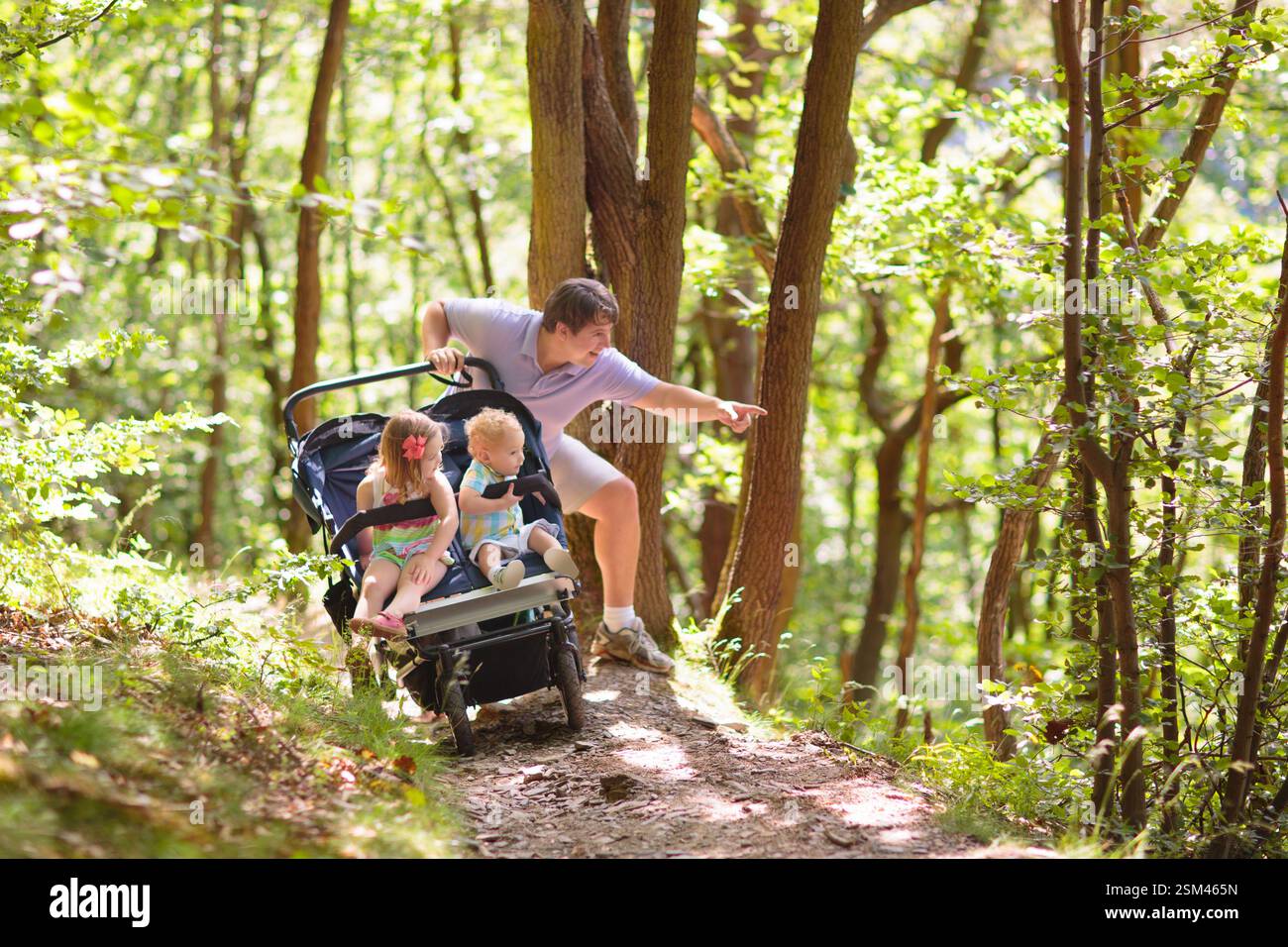 Young father walking in a park with children in stroller. Dad and kids ...