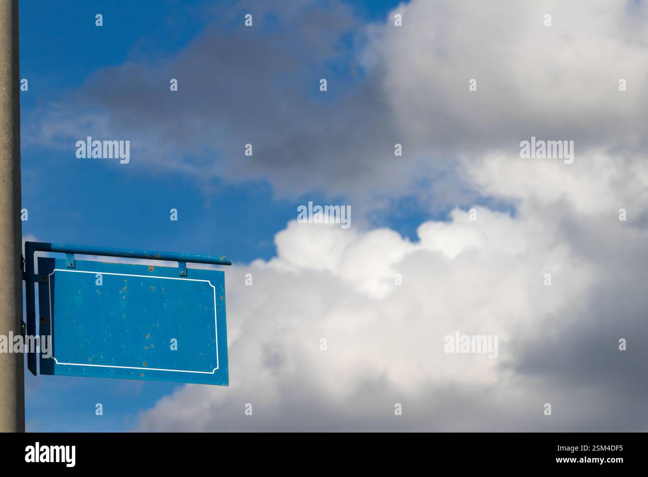 Blue rectangular metal sign with decorative border mounted on a pole ...