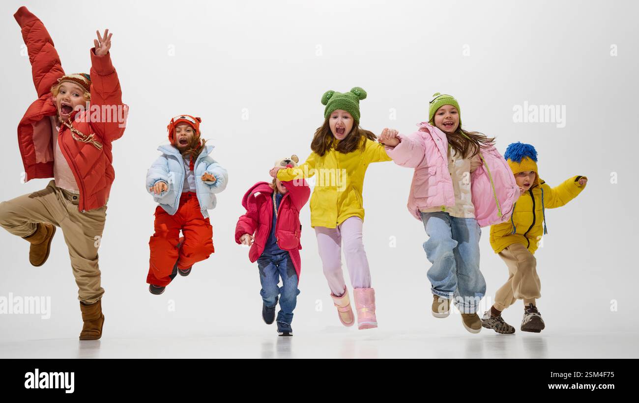 Group of children, jumping high, wearing colorful winter outfits ...