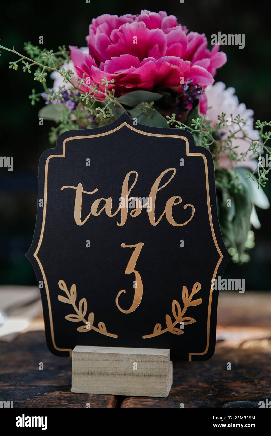 A stylish table sign labeled as number three rests beside a vibrant ...