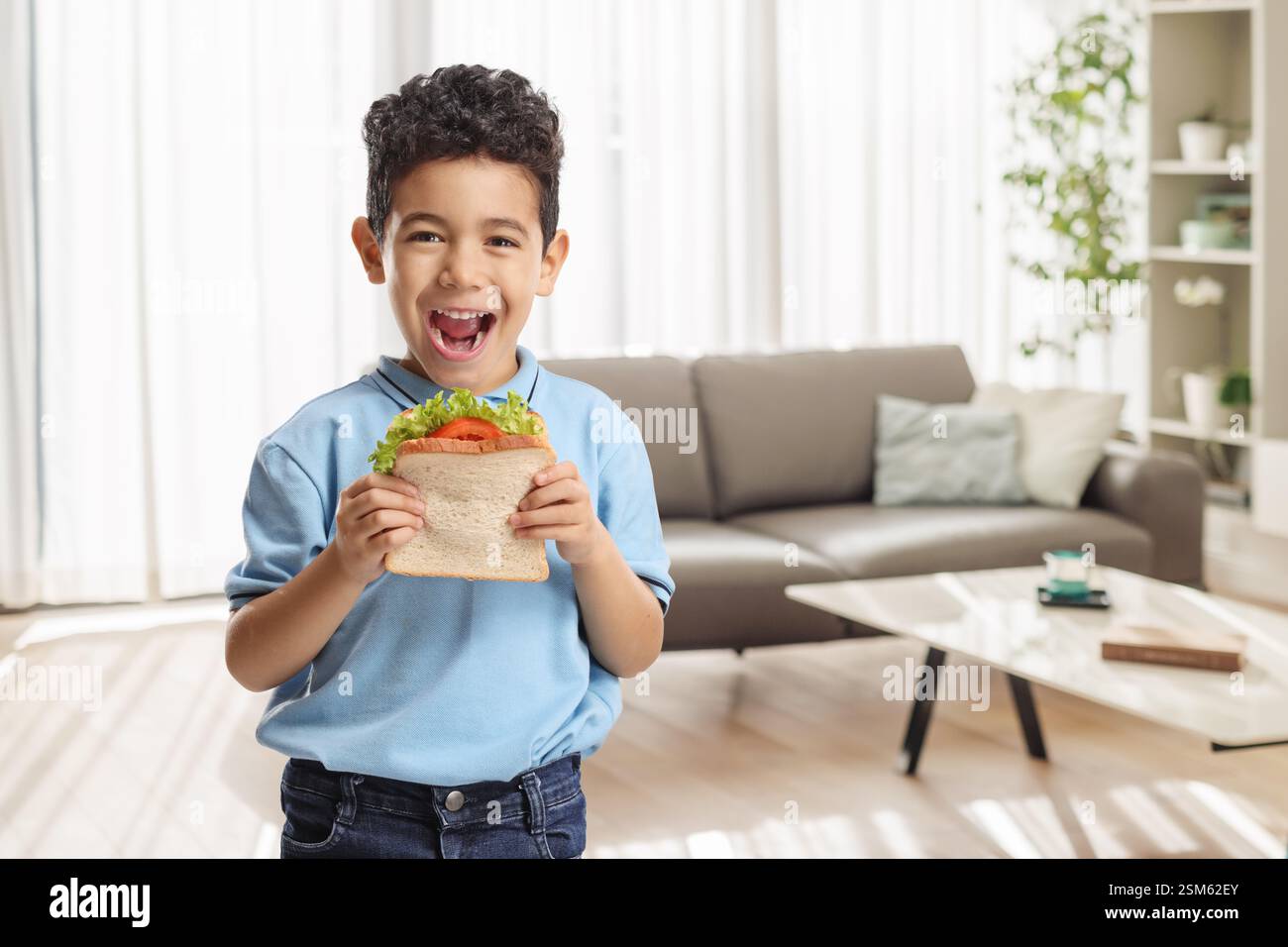 Hungry boy eating a sandwich at home in a living room Stock Photo - Alamy