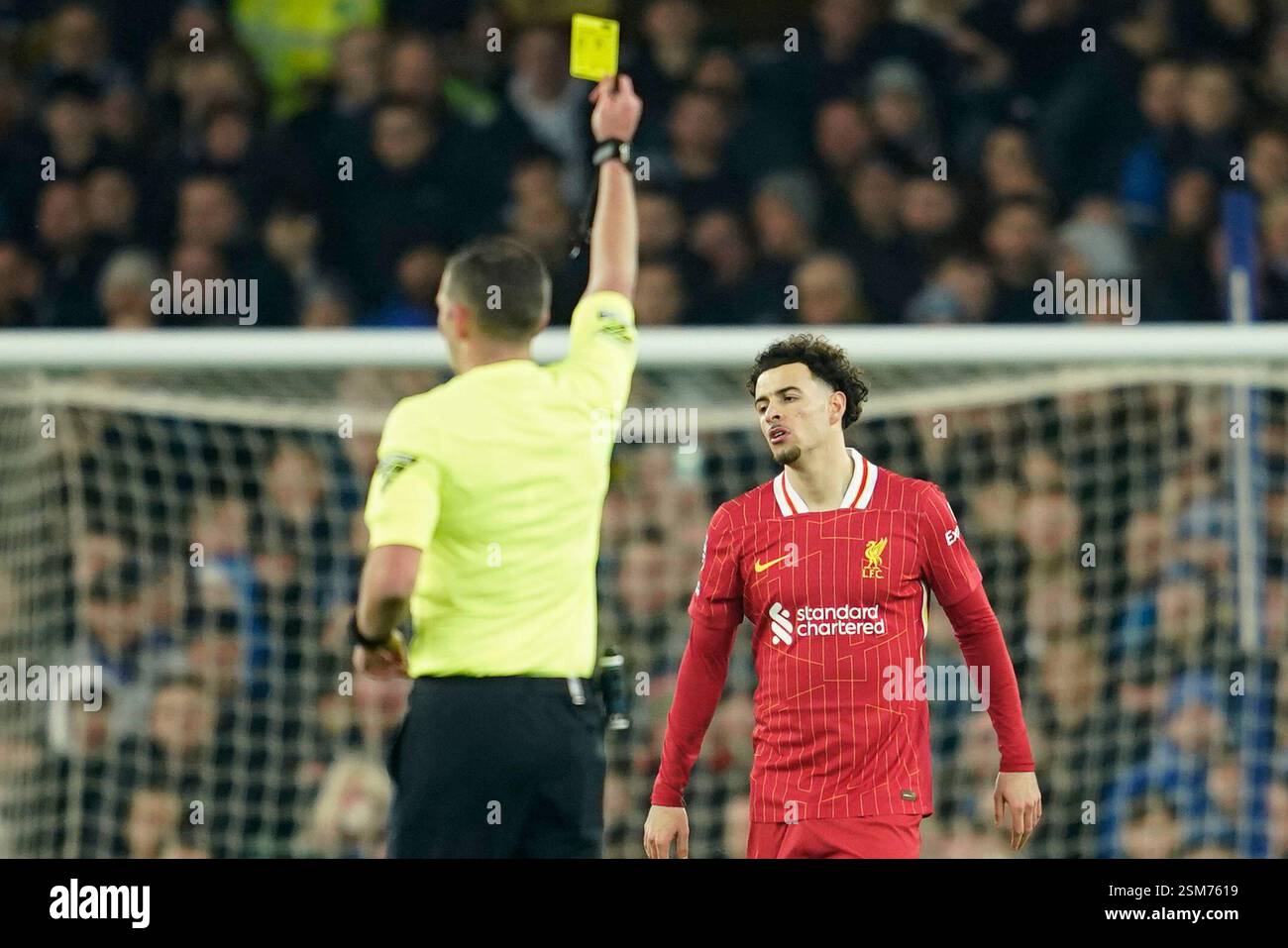 Referee Michael Oliver shows a yellow card to Liverpool's Curtis Jones ...