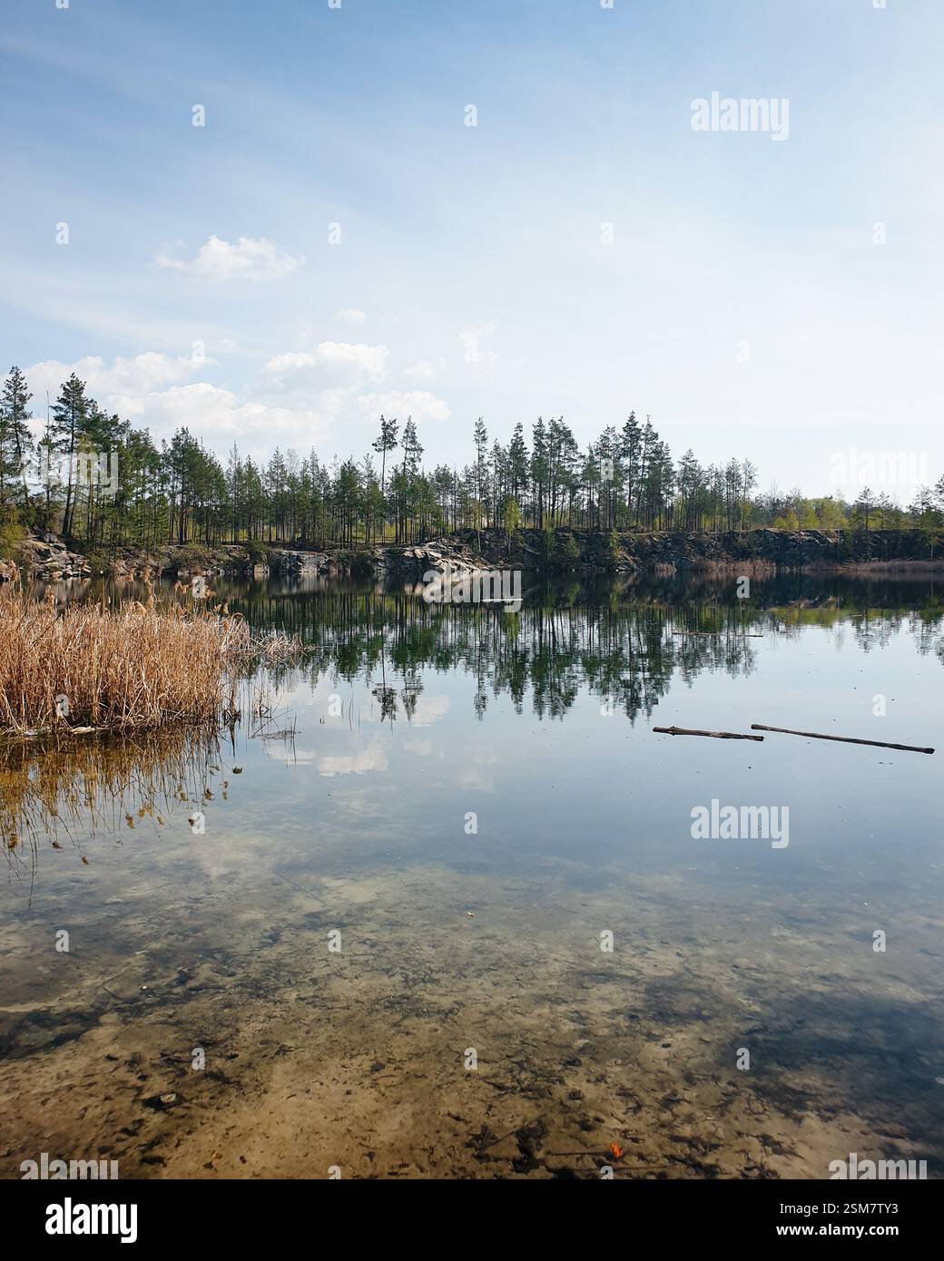 Quarry lake with rocky banks on a sunny day. Reflection of trees and ...