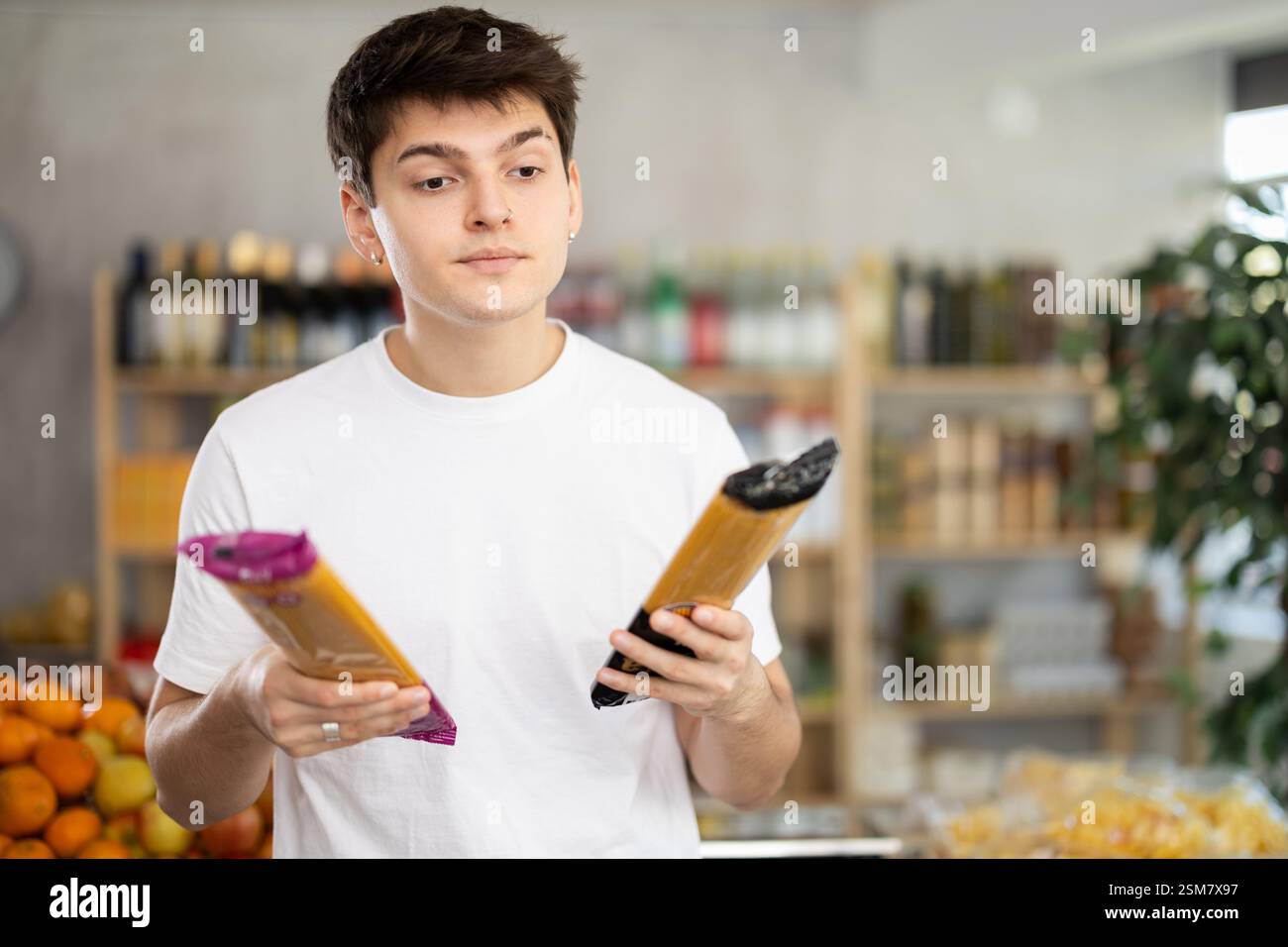 Young guy comparing two spaghetti packs in grocery store Stock Photo ...
