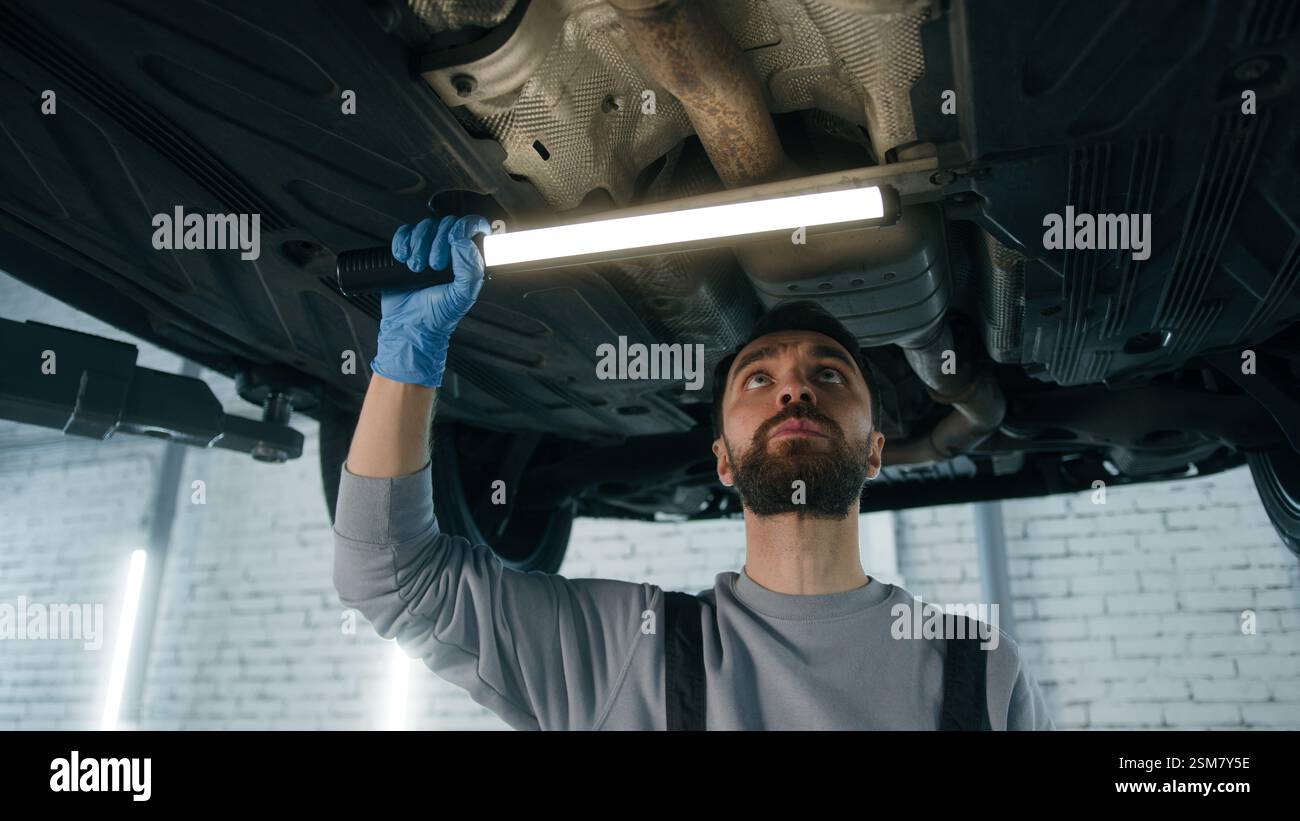 Caucasian man guy repairman auto mechanic working underneath lifting ...