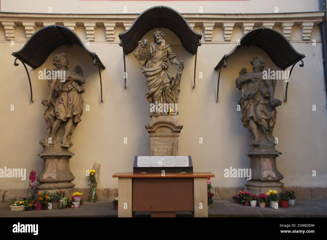 Three statues depicting religious figures stand against a wall, with a ...