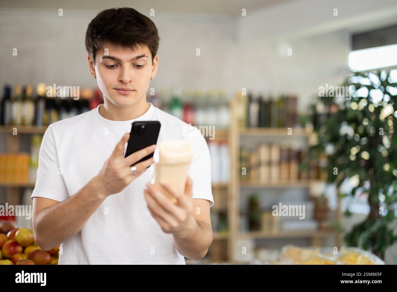 Male buyer checks suitability - scans QR code on jar of mayonnaise ...