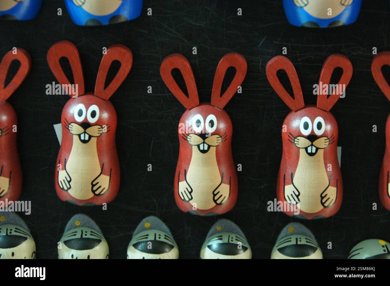 Row of wooden rabbit toys. Brown bodies, red ears and hands, black eyes ...