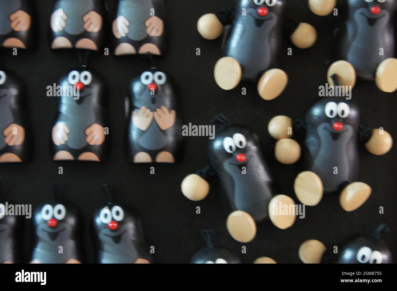 The photo shows 10 small, black, and round toy moles on a black ...