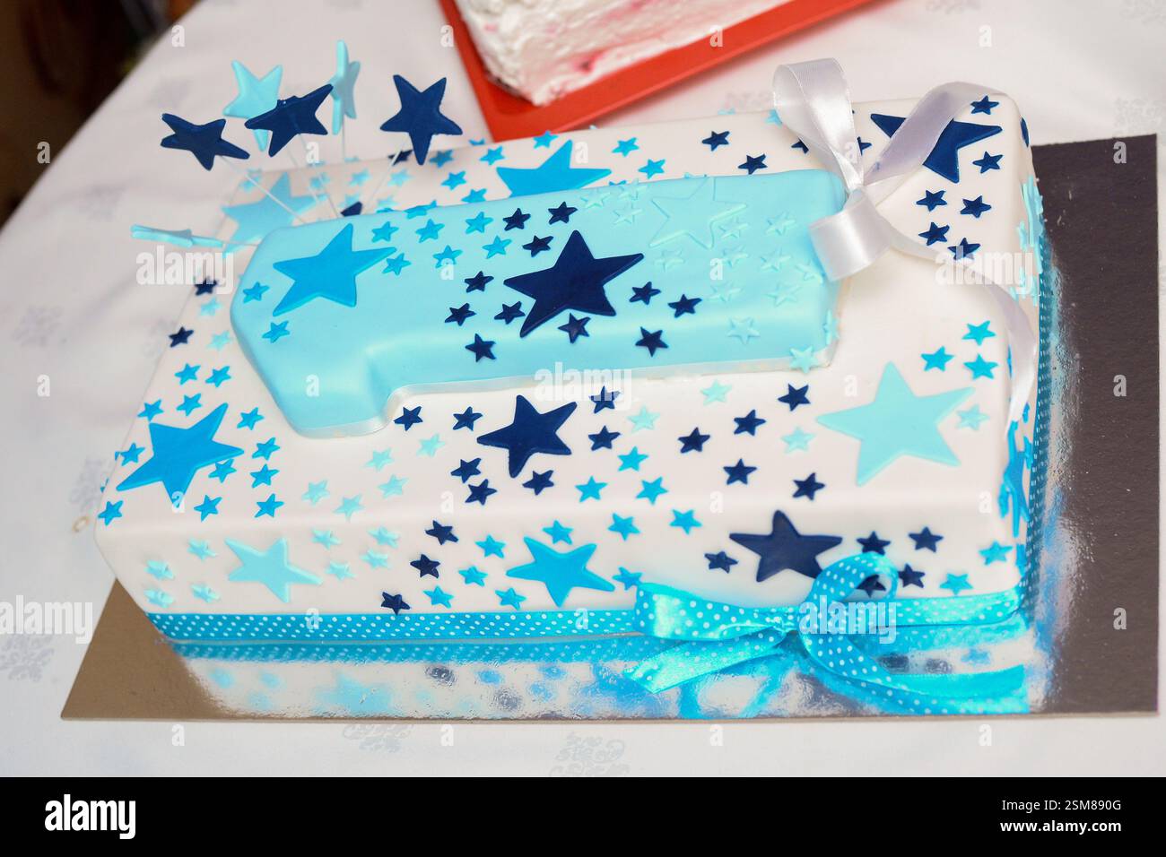 A square birthday cake with a large number one and various shades of ...
