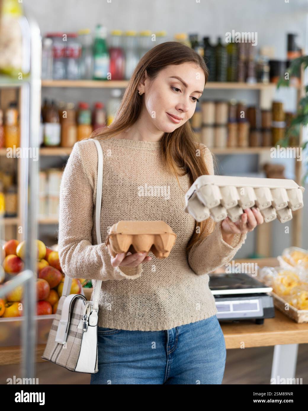 Young woman comparing egg cartons in grocery store Stock Photo - Alamy