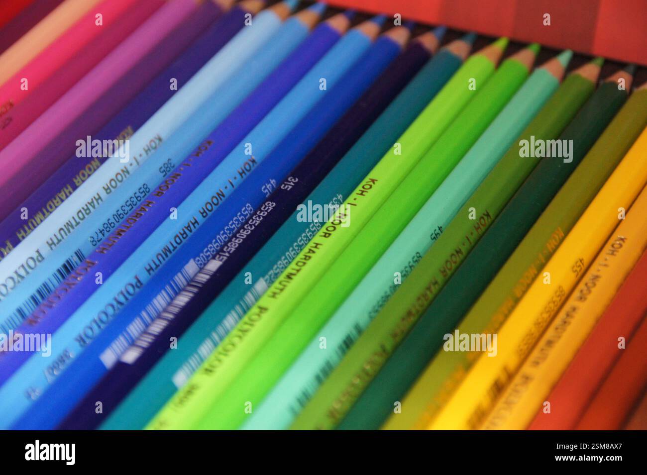 The photo shows a close-up of a box of colored pencils arranged by ...