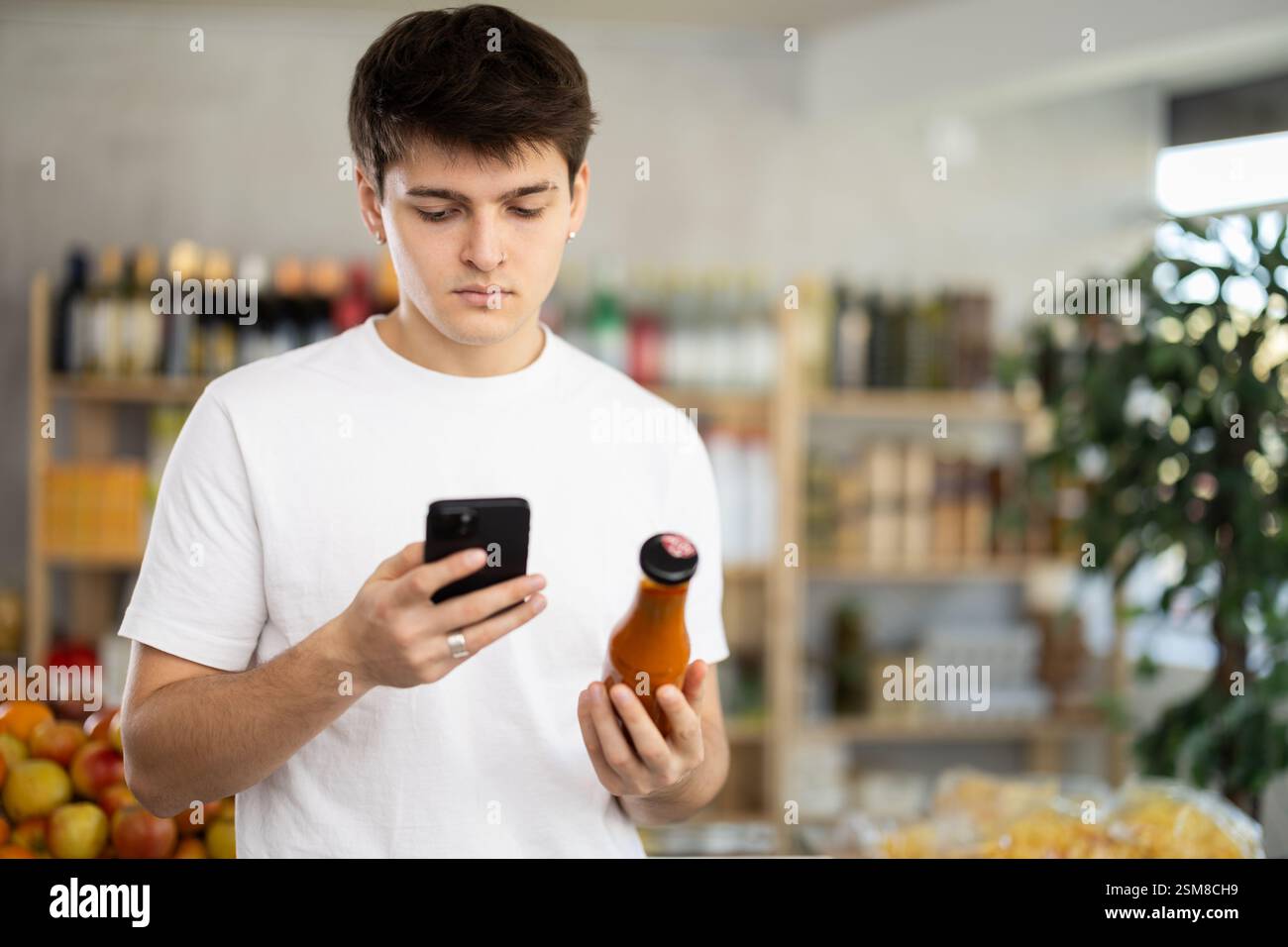 In shop young man scans QR code and take reading on sauce package using ...