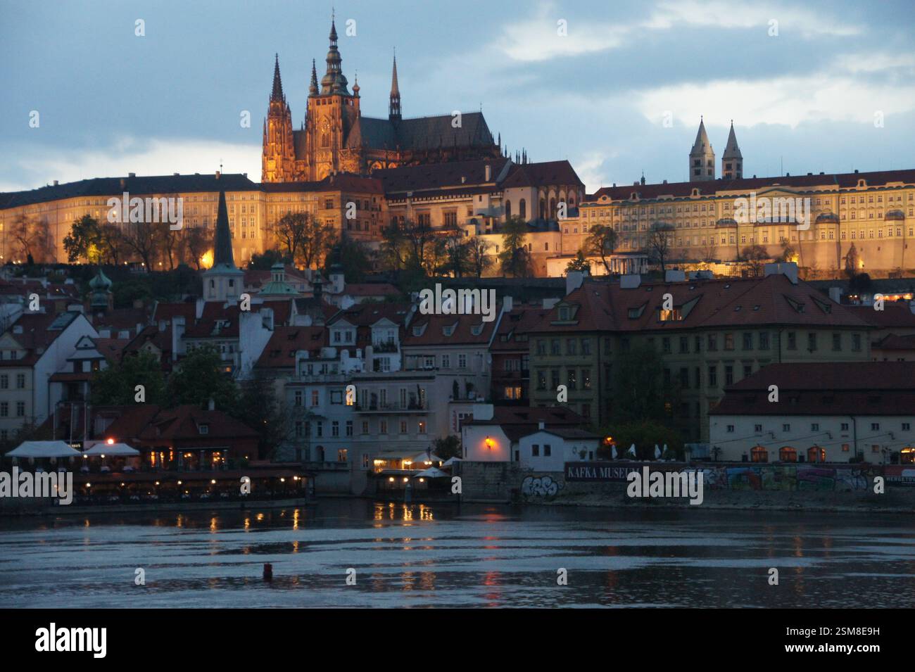 Prague Castle, illuminated spires and towers against a darkening sky. A ...