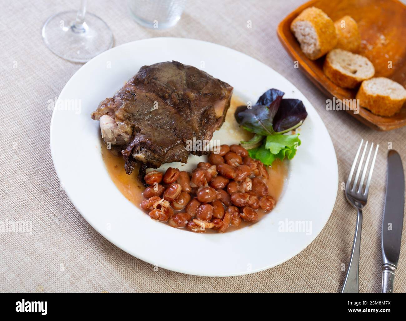 Baked pork cheek with stewed pinto beans and greens Stock Photo - Alamy