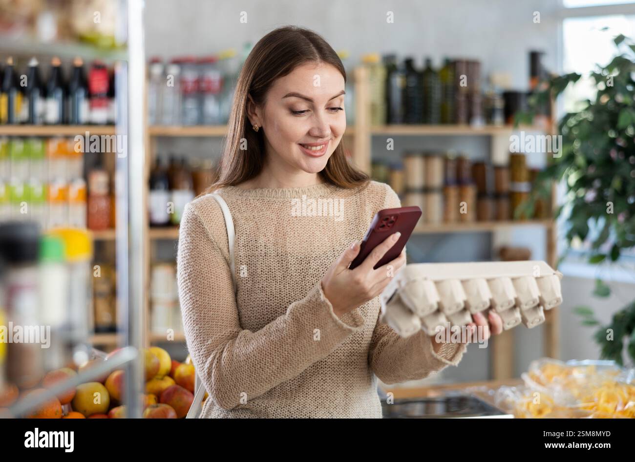 Woman scanning barcode on egg carton with phone in supermarket Stock ...