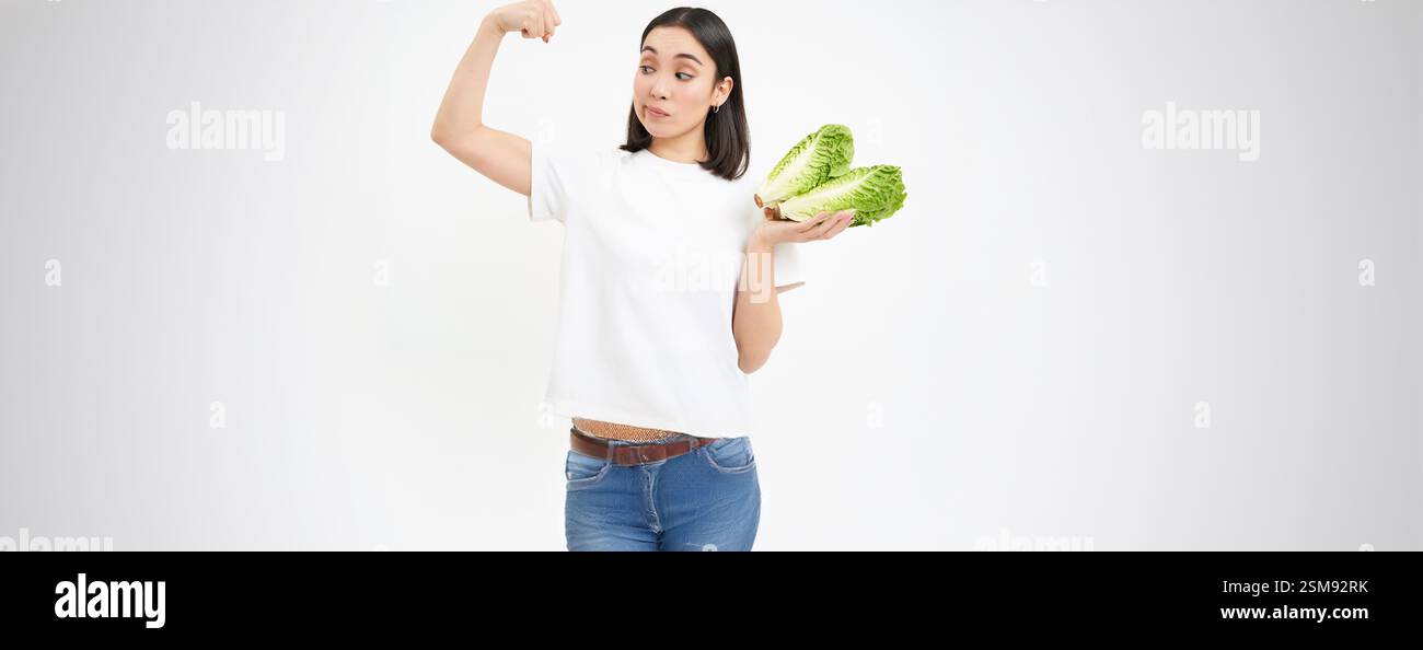 Diet and health. Smiling asian woman shows her biceps, strong body and ...