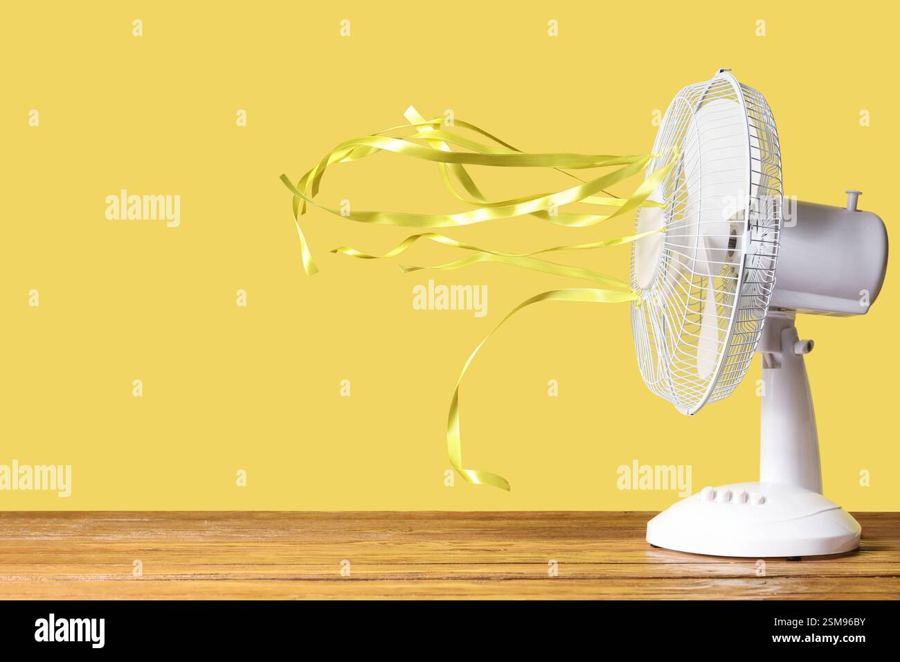 Electric fan with fluttering ribbons on yellow background Stock Photo ...