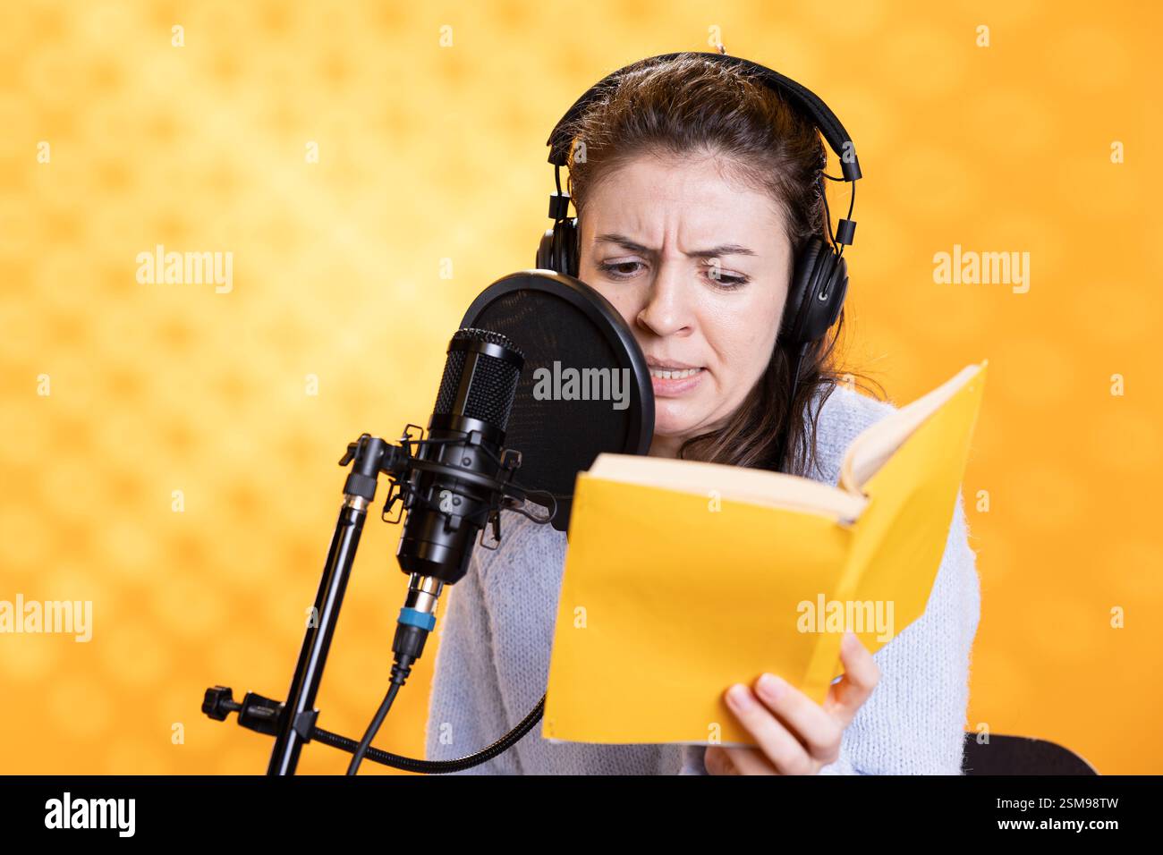 Narrator frowning while reading book, recording audiobook using ...