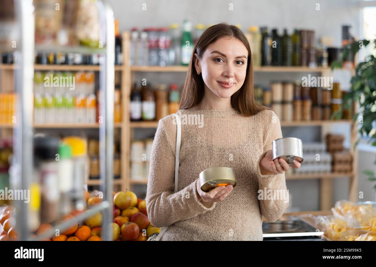 Female shopper choosing canned food in grocery store Stock Photo - Alamy