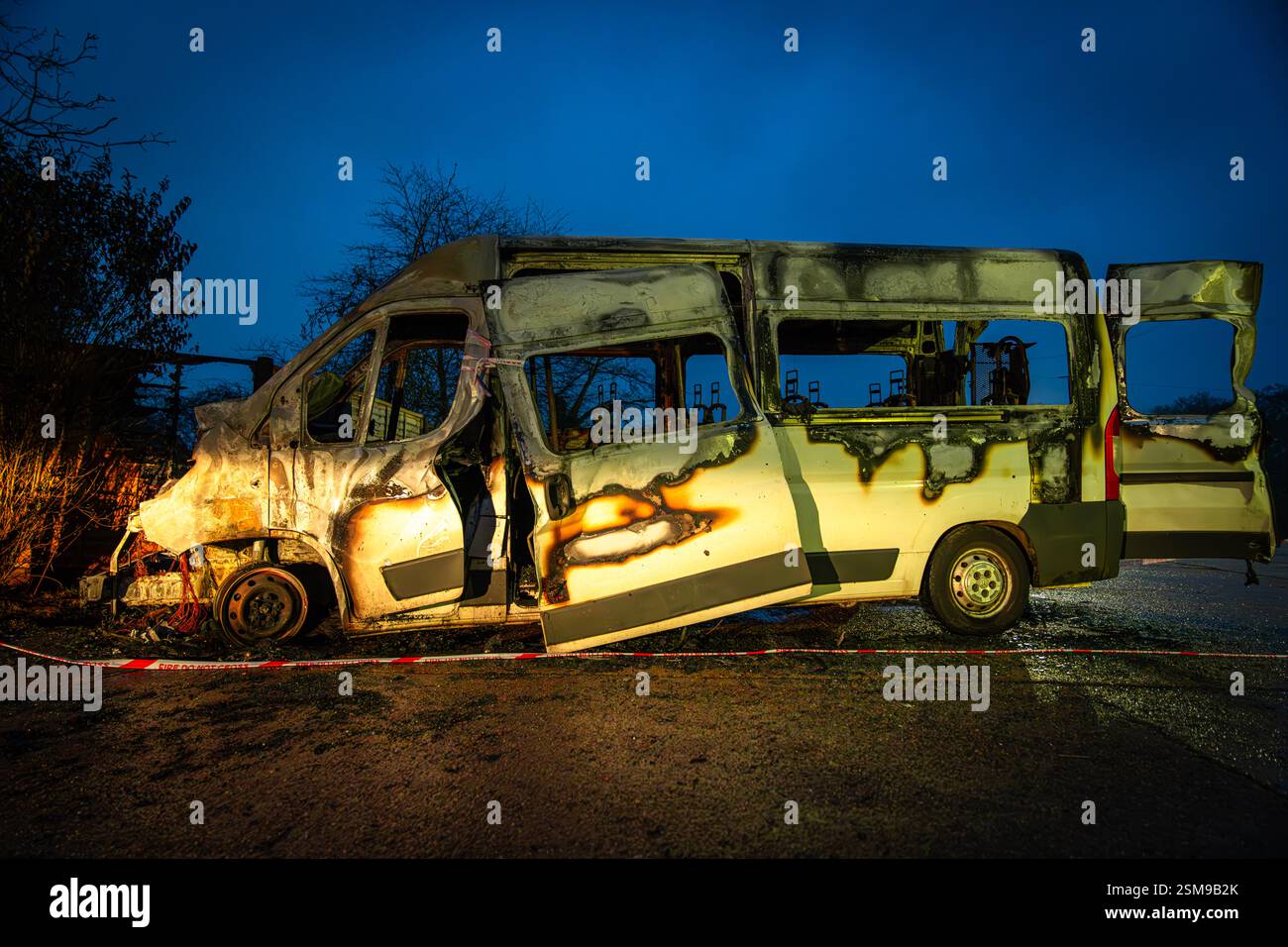 White van destroyed by fire at night, showing extensive fire damage ...