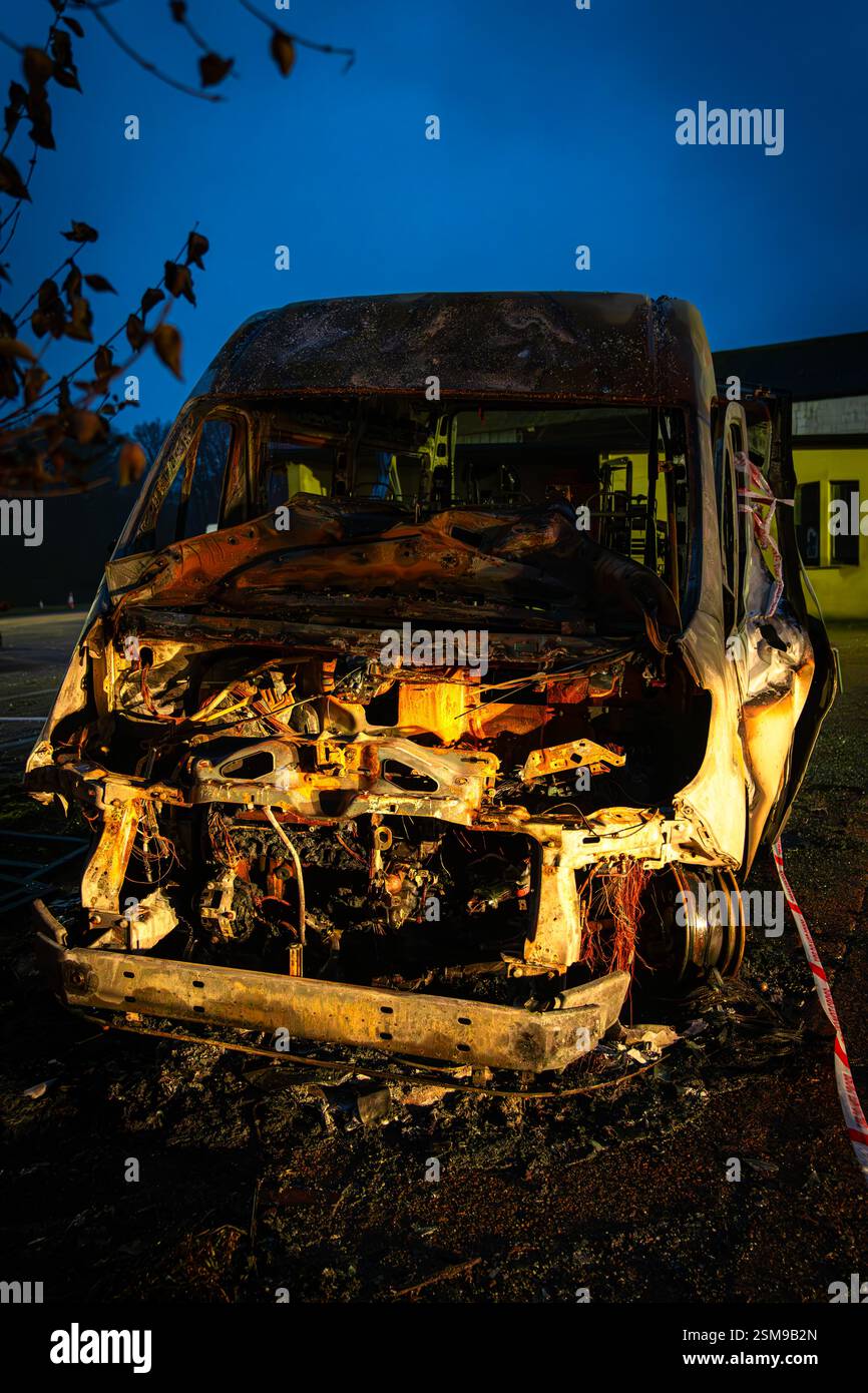 Destroyed rusty van revealing its engine and interior, parked near a ...