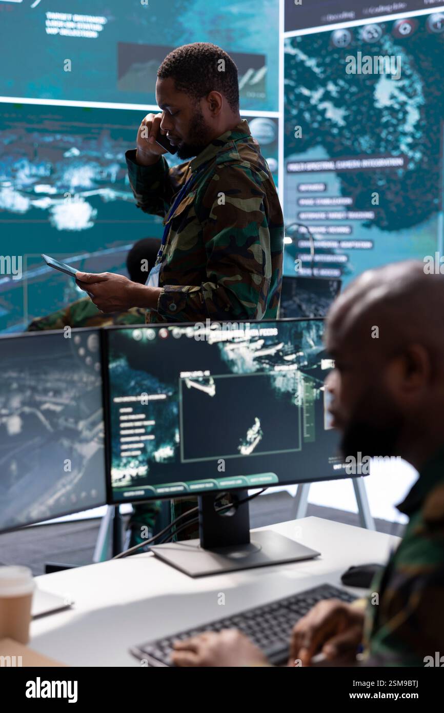 Soldier discussing on phone call in a modern control room, processing ...