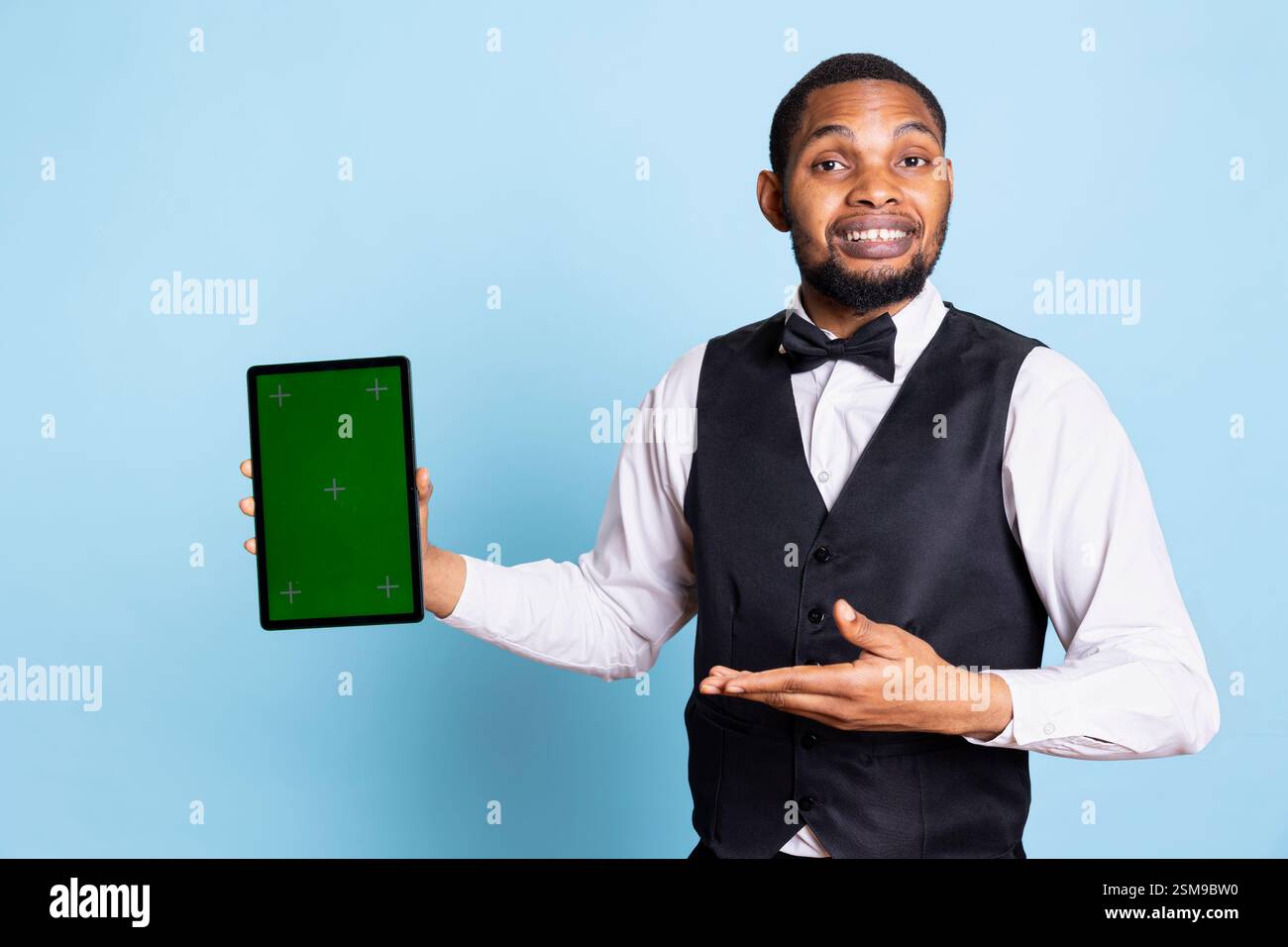 Doorkeeper bellboy poses with green screen on tablet at the hotel ...