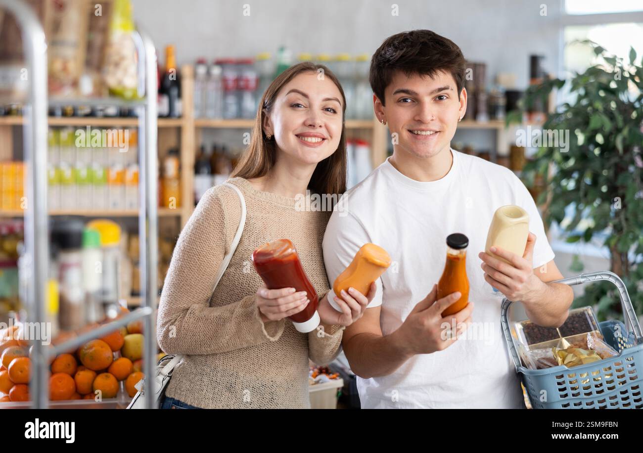 Married young happy couple chooses spicy sauce in supermarket Stock ...