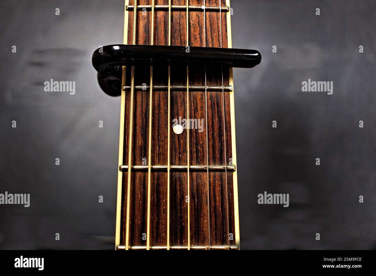 Photo of a guitar neck and strings with a capo clamped to it Stock ...