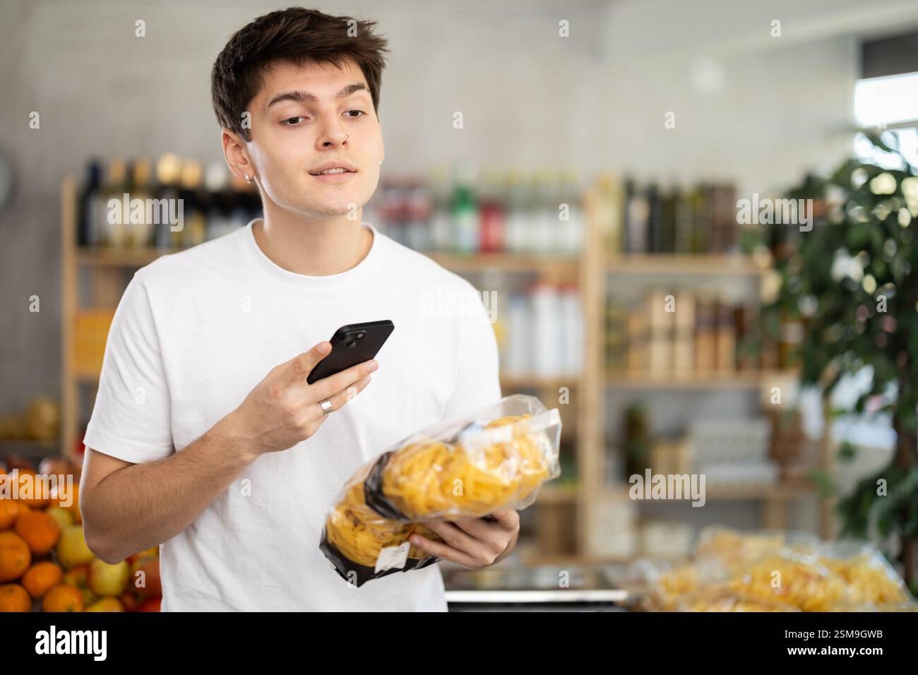 In shop young man scans QR code and take reading on pasta package using ...