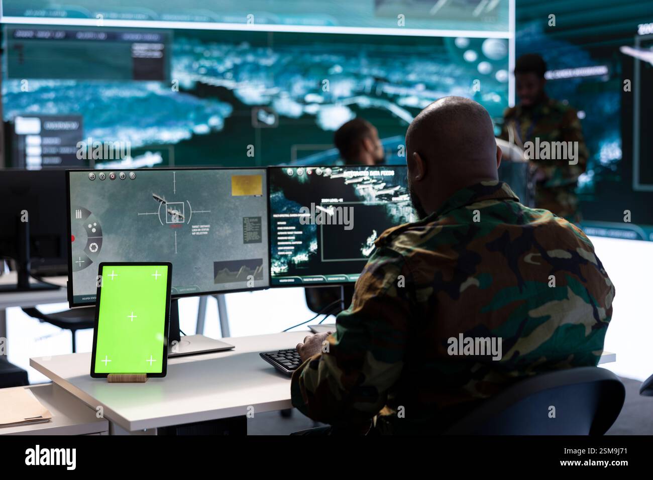 Military man works in command post working on collecting real time data, intelligence gathering ...