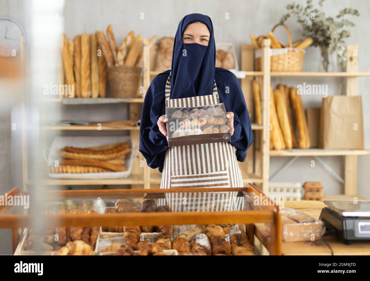 European Muslim woman bakery worker sells cookies in box, stand at ...
