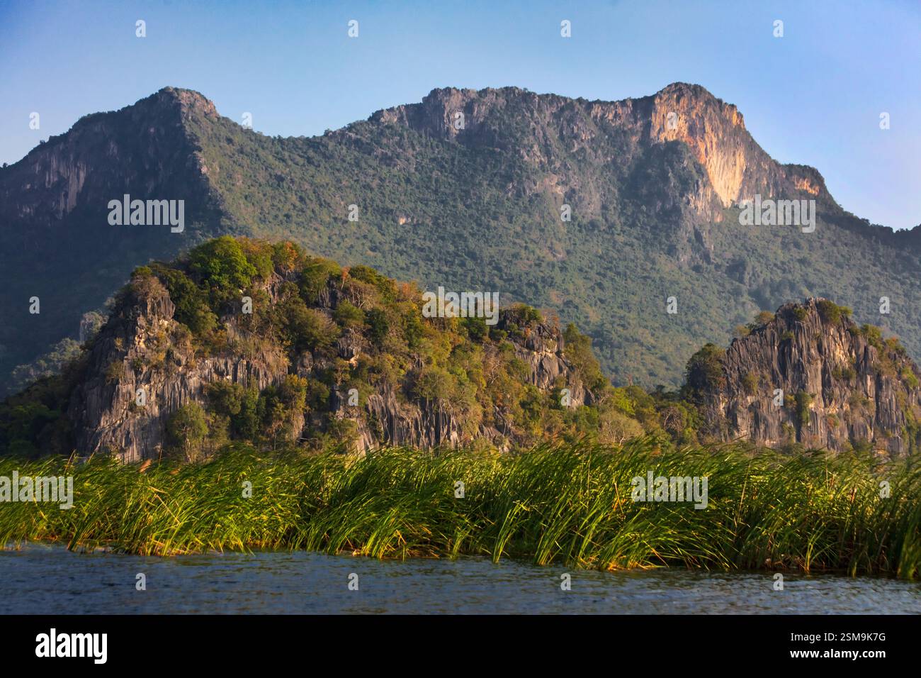 Limestone mountains rise above reeds growing in the inland waterways of ...