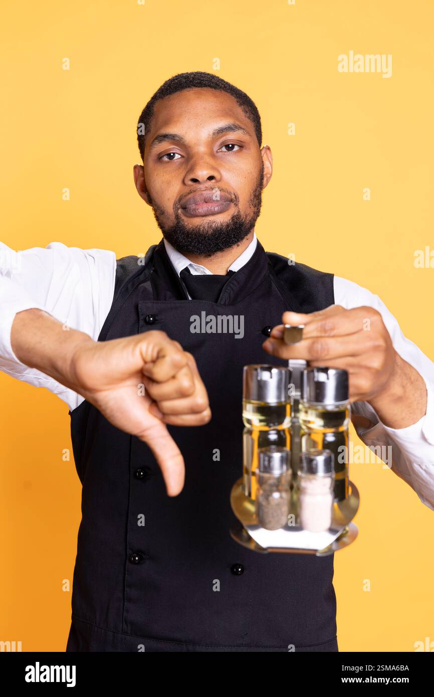 Professional waiter showing a thumbs down symbol in studio, showing his ...