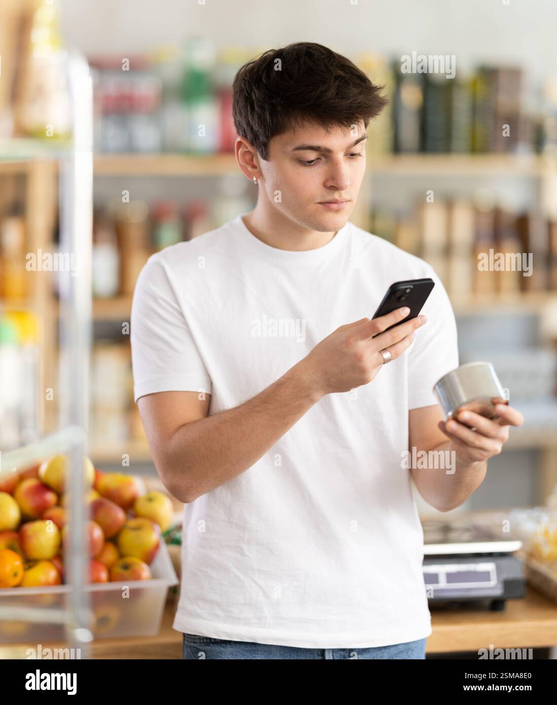 Guy scanning barcode on canned food while shopping in grocery store ...