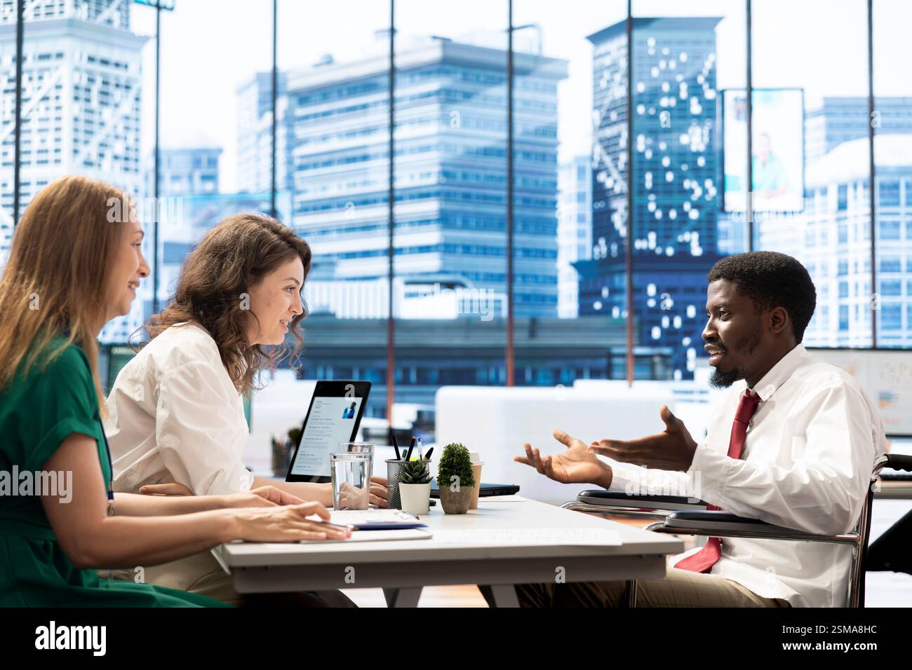 Professional in wheelchair collaborating with colleagues in office ...
