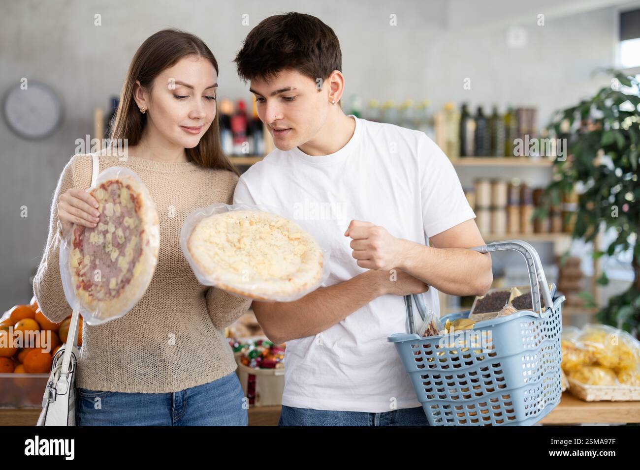 Happy young wife and husband choose large and fresh pizza in ...