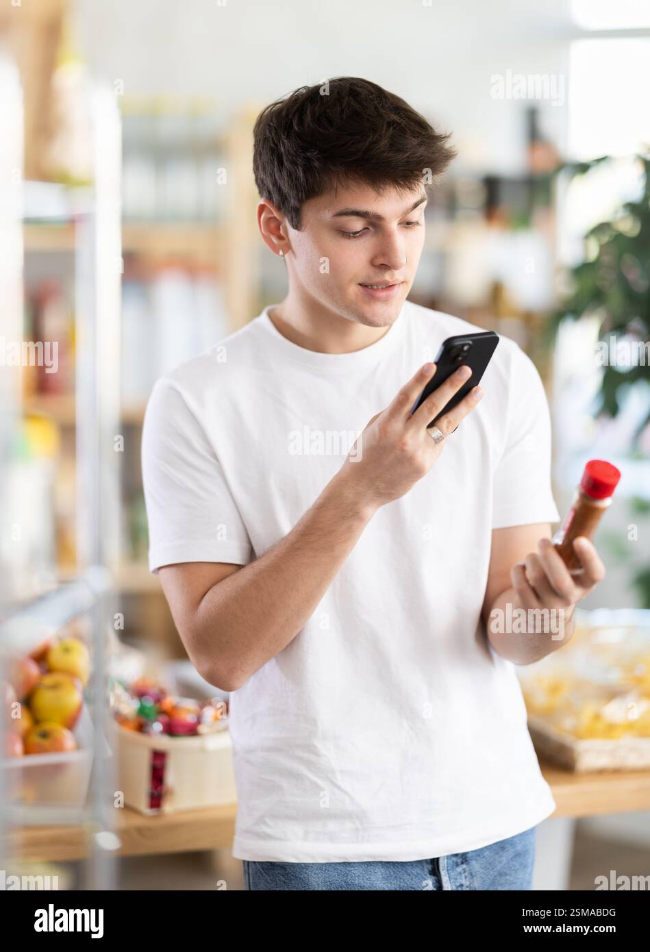 Guy scanning QR code on bottle of red pepper with phone Stock Photo - Alamy