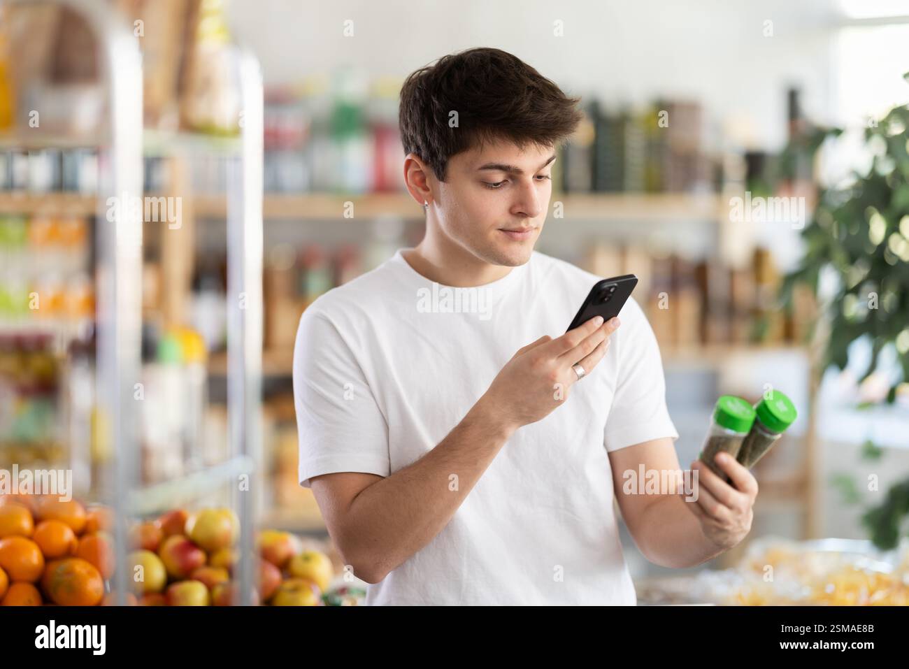 Guy scanning QR code on bottle cardamom label in grocery department of ...