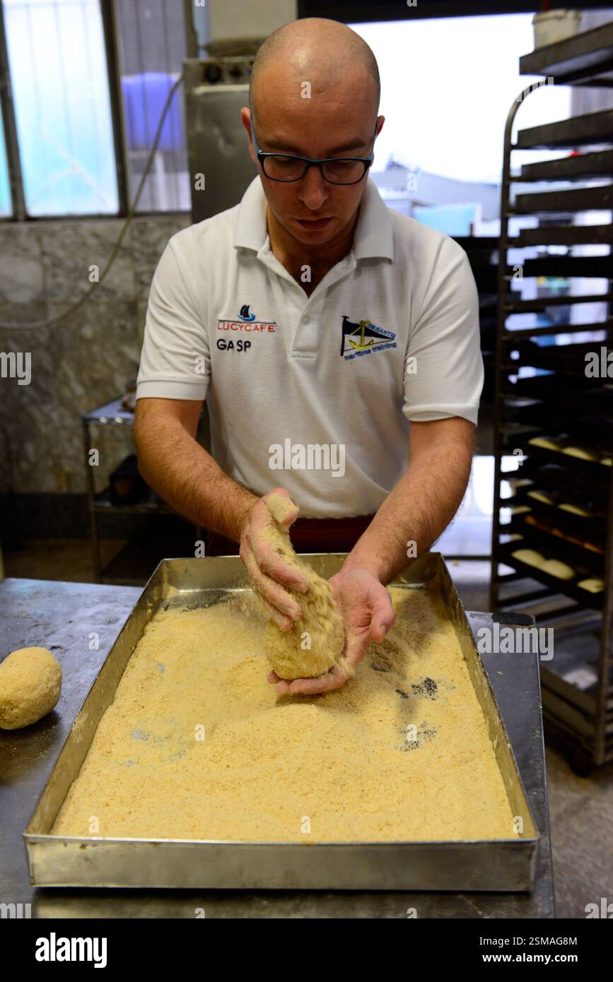 A chef preparing Arancini in a kitchen of a snack bar in Palermo, Italy ...