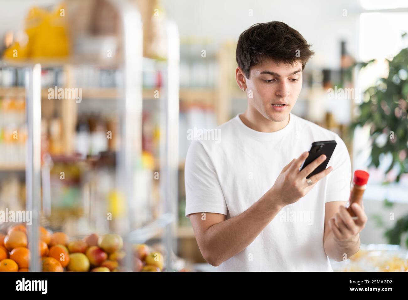 Guy scanning QR code on bottle of red pepper with phone Stock Photo - Alamy