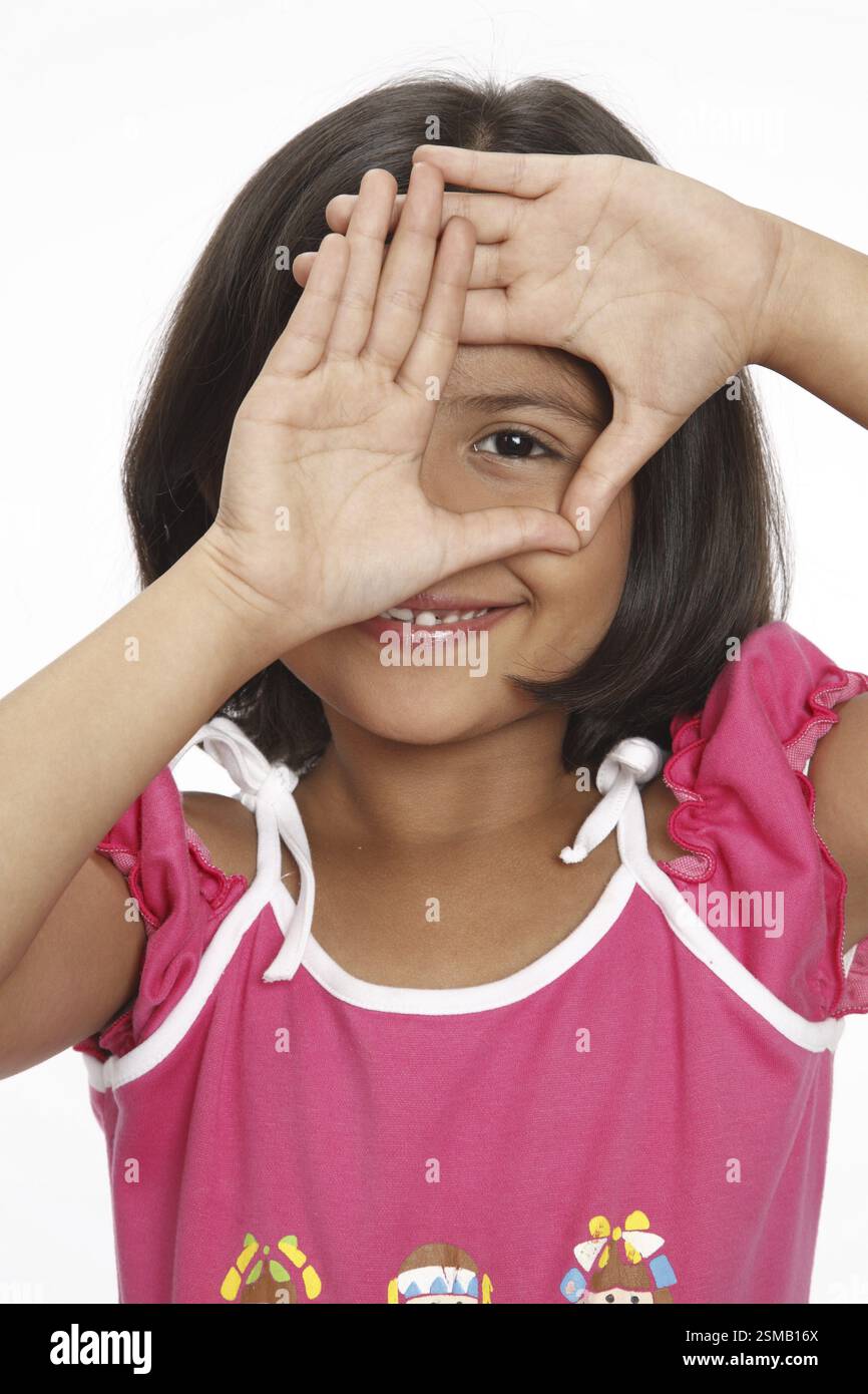 Eight year old girl joining both palms to make window between both ...