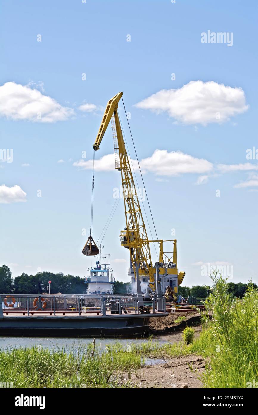 Loading sand with the help of a yellow crane on a barge. River White ...