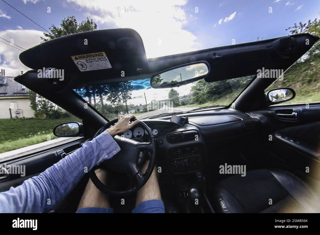 Interior view of a convertible driving on an open road under a blue sky ...