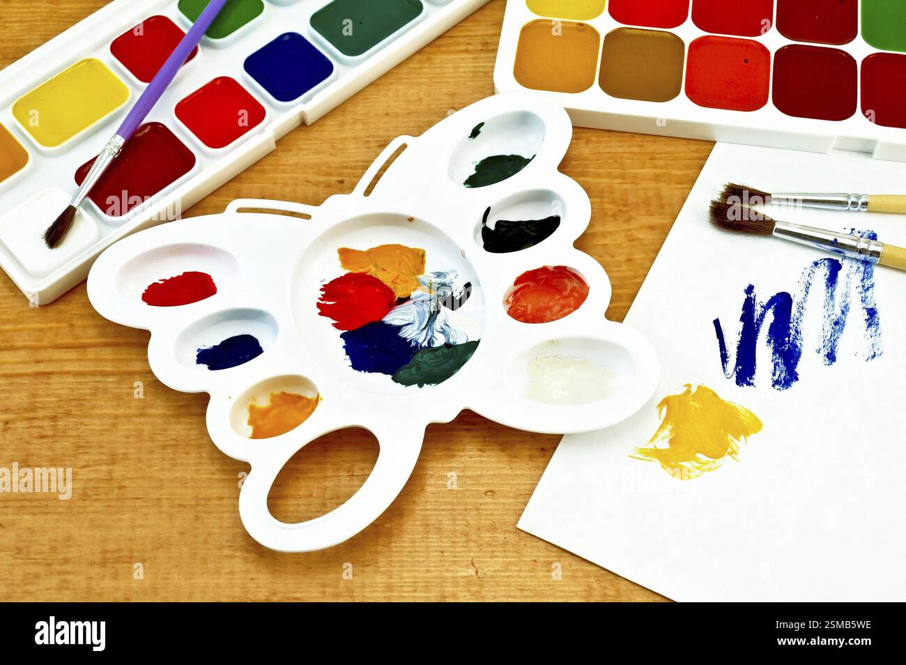 Two boxes of paint, three brushes, white palette in the shape of a ...