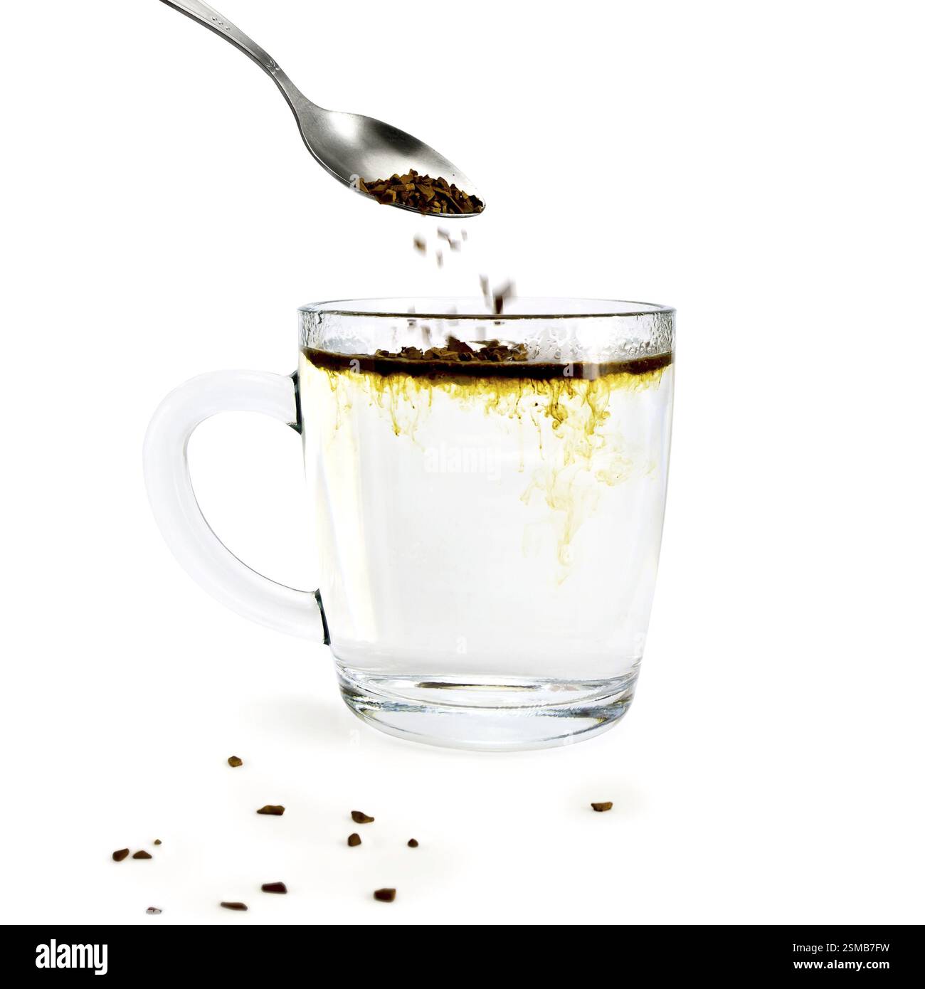 Granulated Coffee poured from a spoon into a glass mug with hot water ...