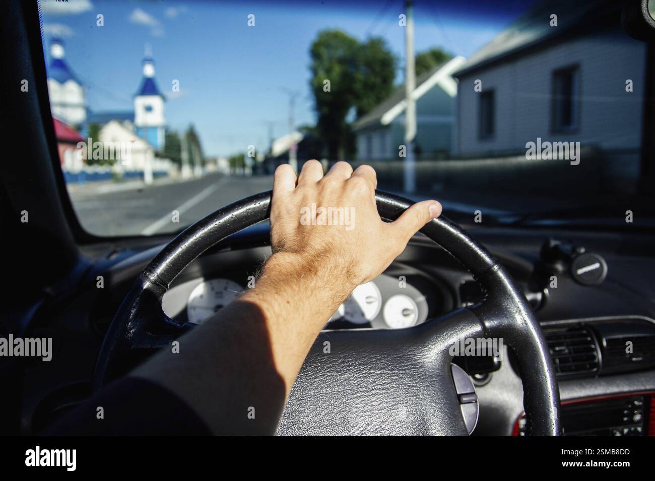 Driver's perspective with hand on steering wheel, sunny day and clear ...