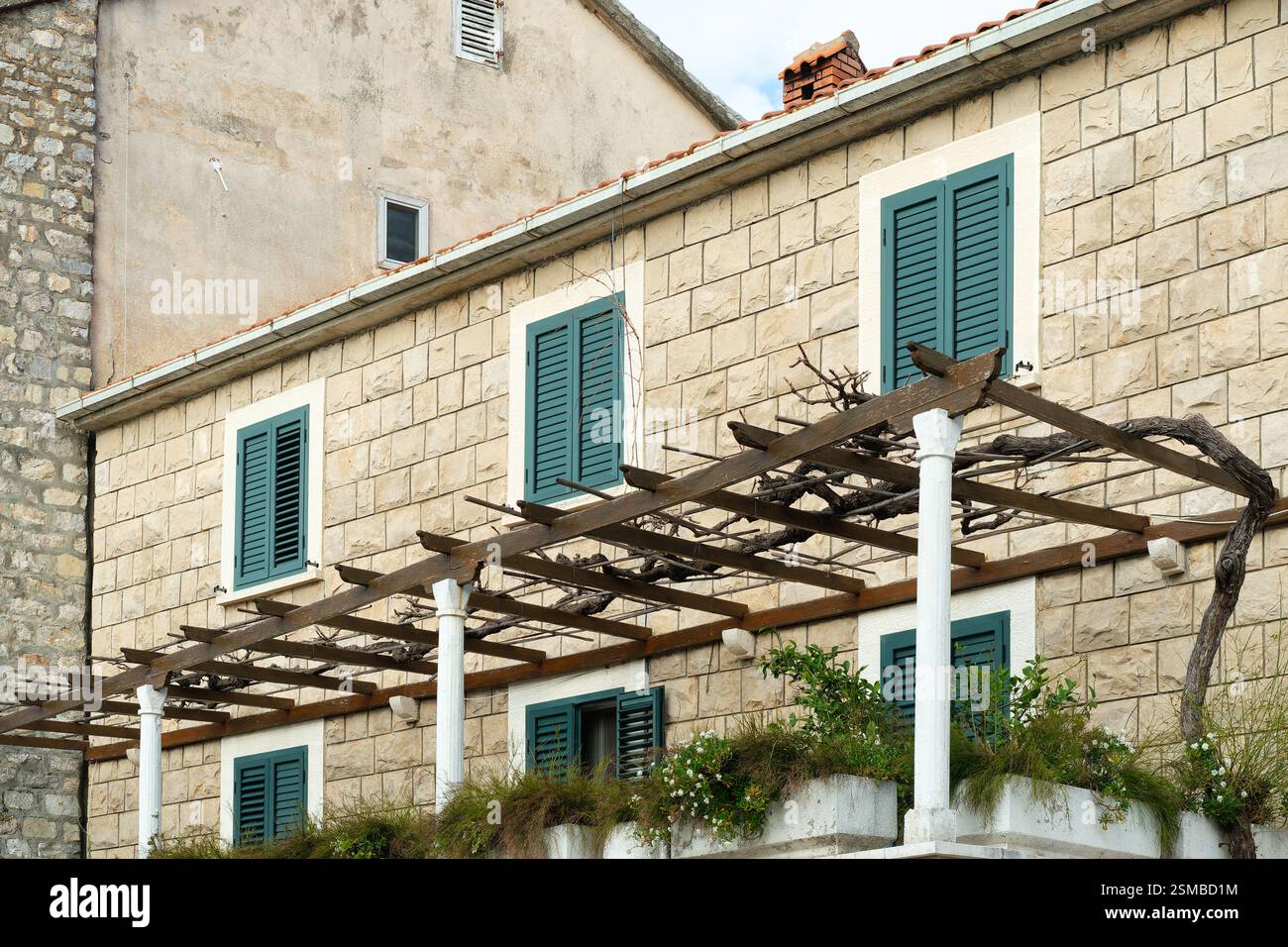 Traditional Mediterranean stone house with green shutters and a pergola ...